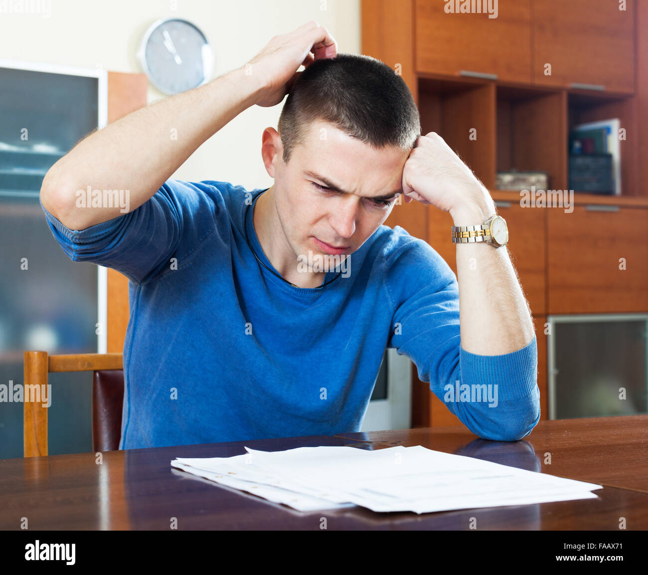 Sad frustrated man looking at financial document and scratching head ...