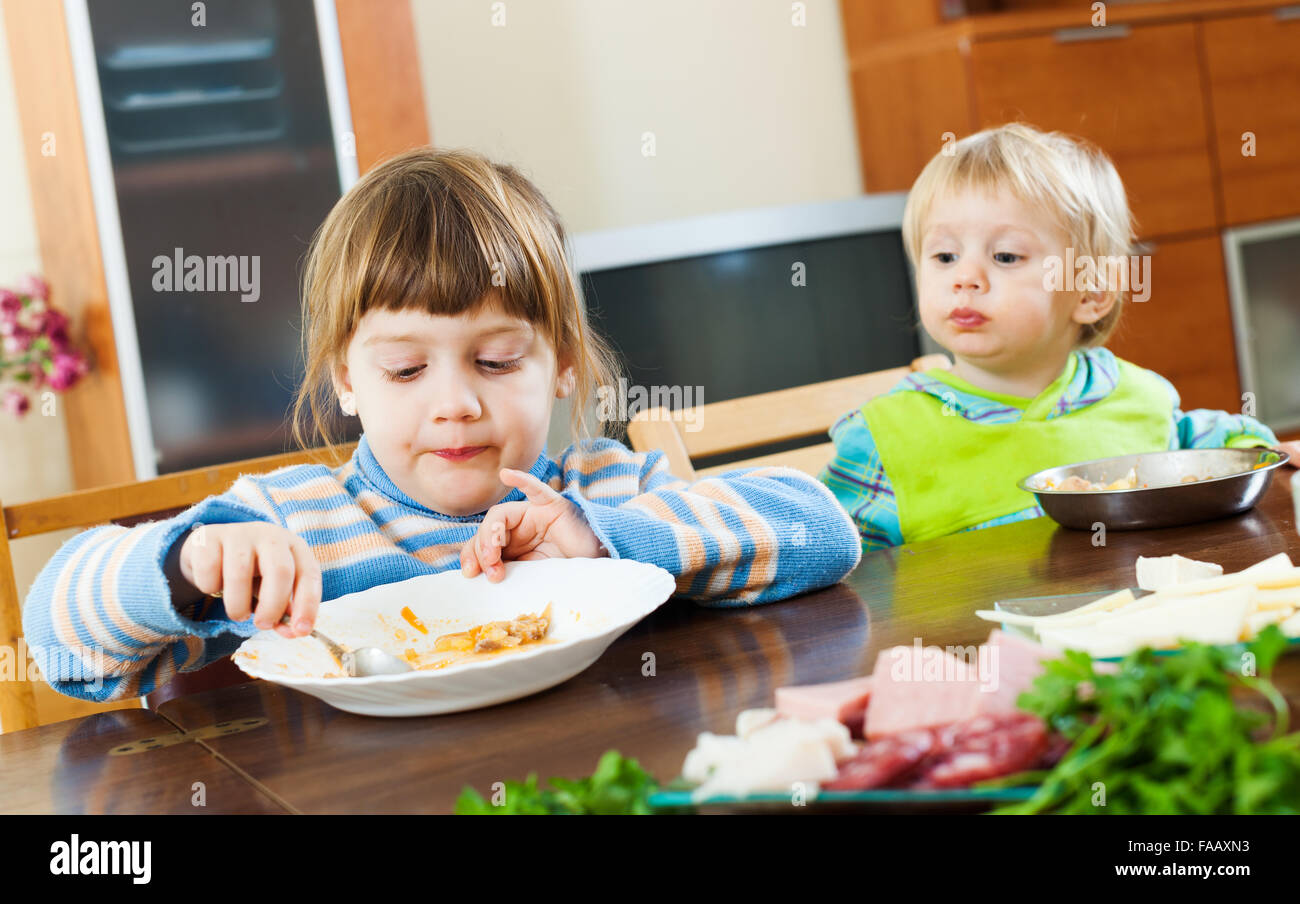 siblings together eating food at wooden table Stock Photo - Alamy
