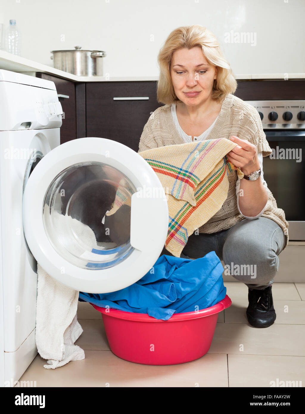 Home laundry. Unhappy woman using washing machine at home Stock Photo ...