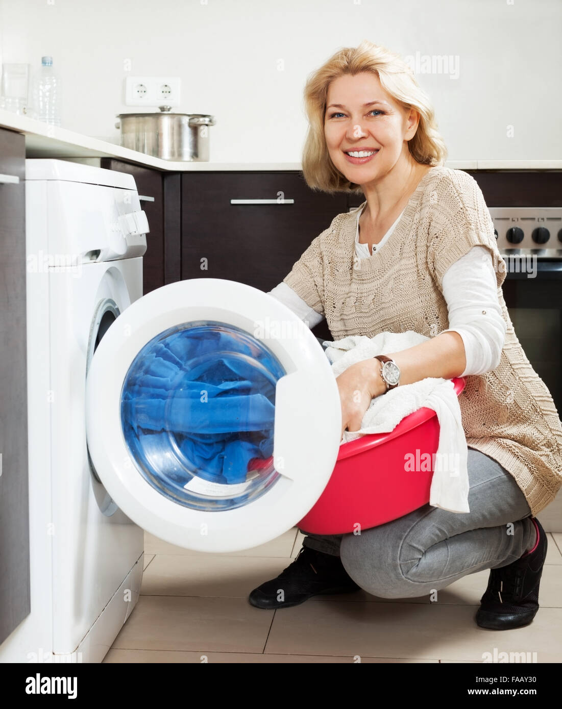 Happy mature woman using washing machine at home laundry Stock Photo ...
