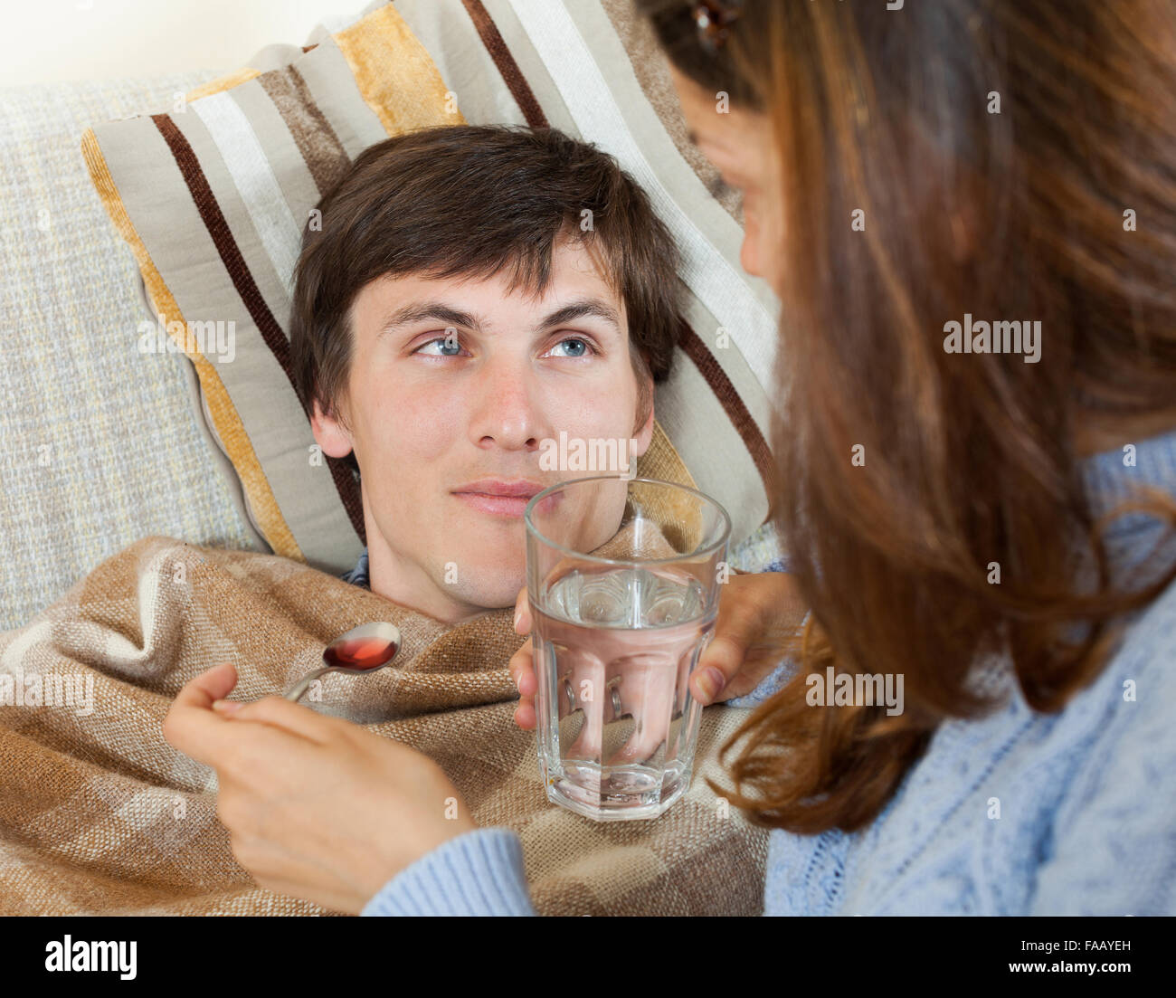 Brunette woman giving medicinal syrup to man at home Stock Photo - Alamy