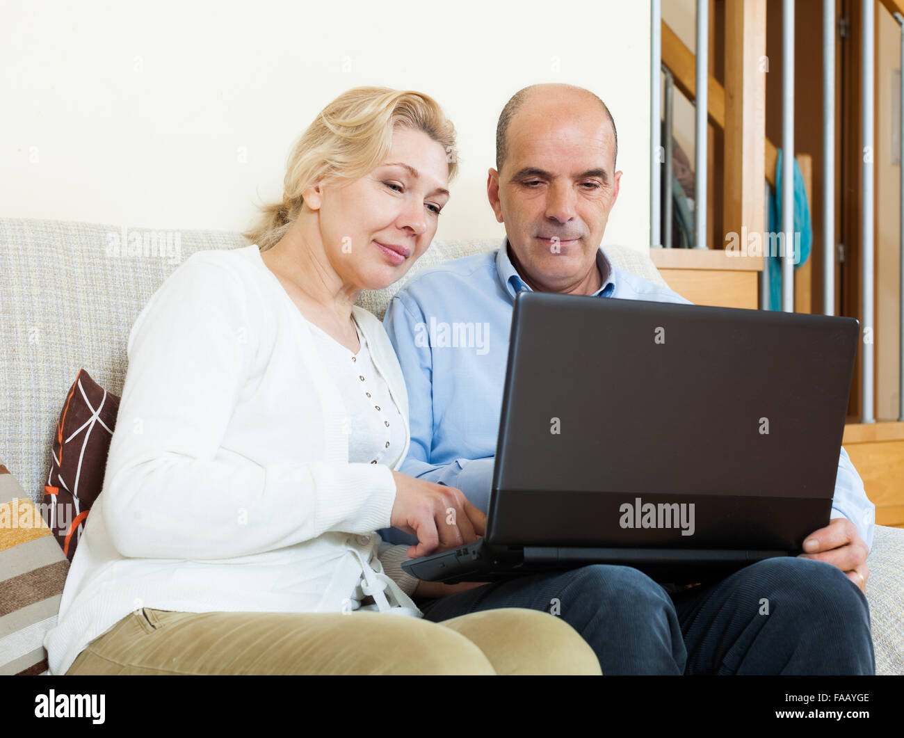 Wistful mature couple with laptop in room Stock Photo - Alamy