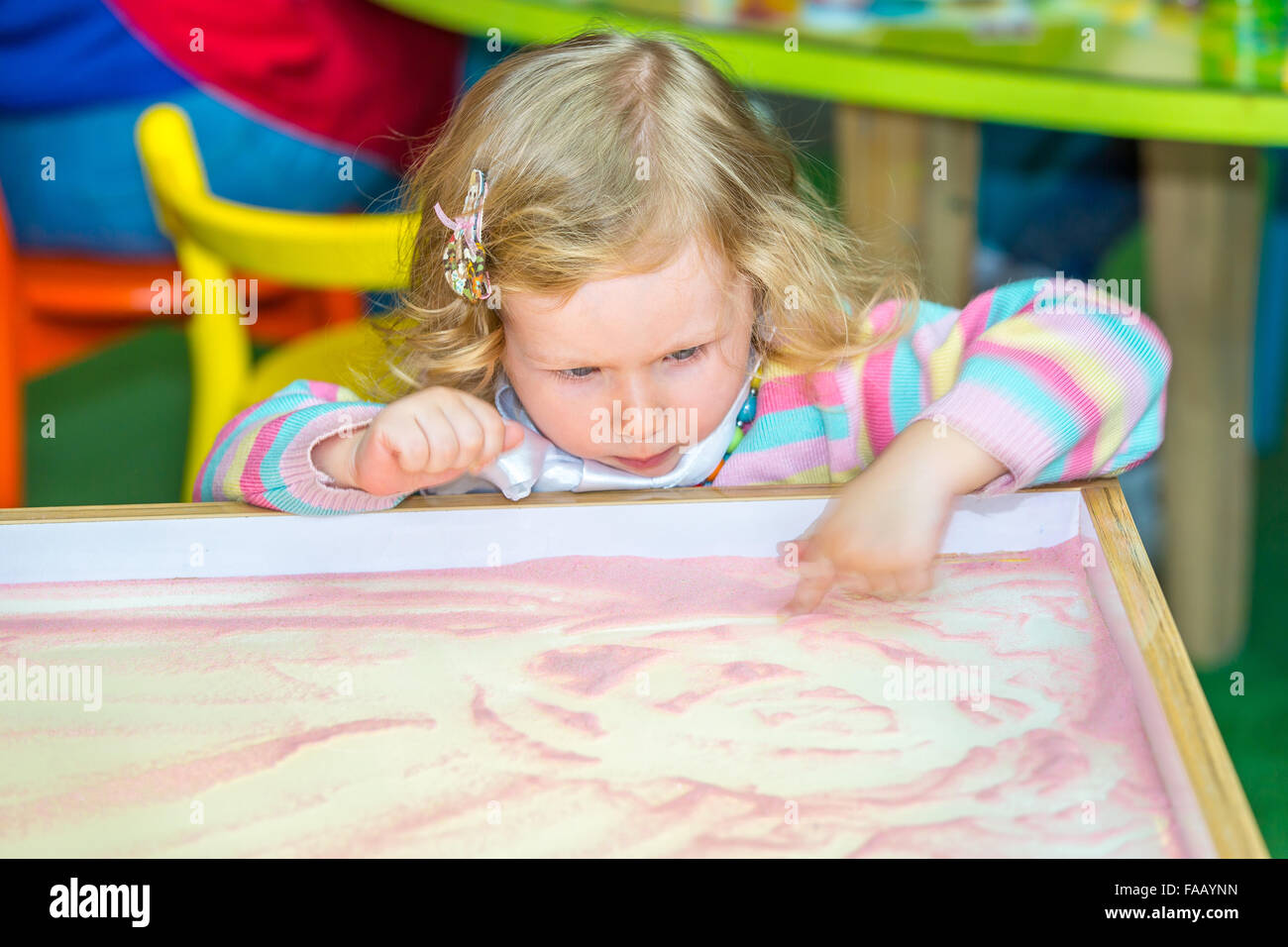 Cute child girl drawing draws developing sand in preschool at table in ...