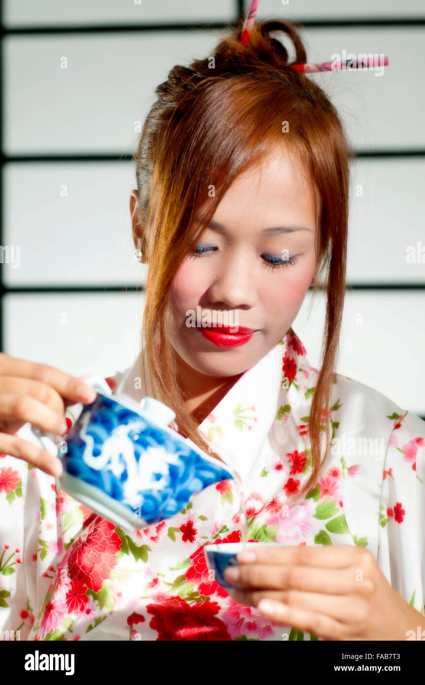 Young Japanese woman drinking tea indoors in studio setting Stock Photo ...