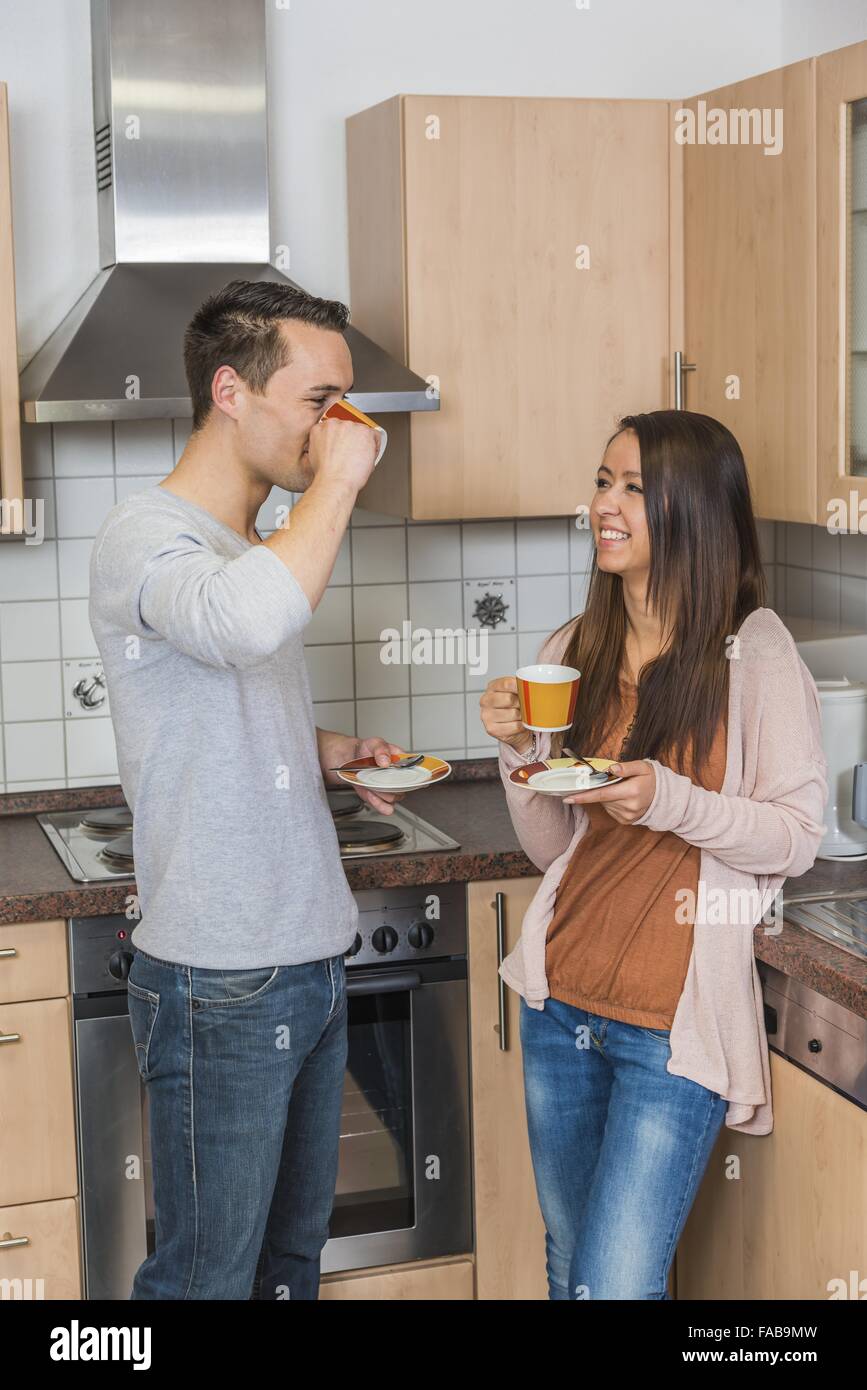 Couple standing in the kitchen drinking coffee Stock Photo - Alamy