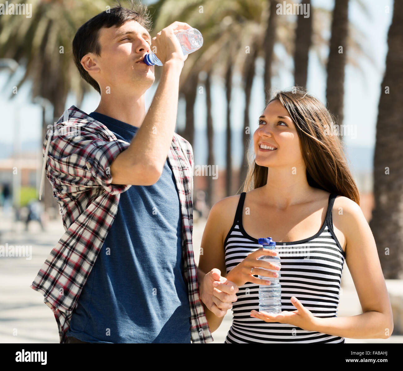 smiling couple enjoying water from plastic bottles outdoor Stock Photo ...