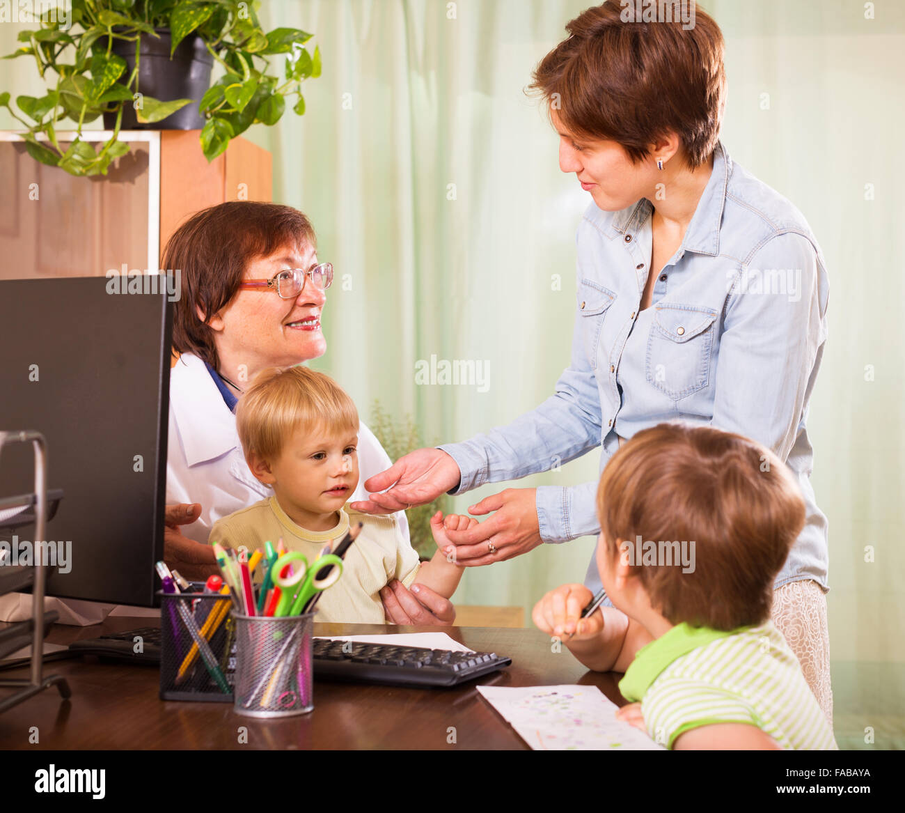 friendly pediatrician doctor examining children with mother at clinic ...