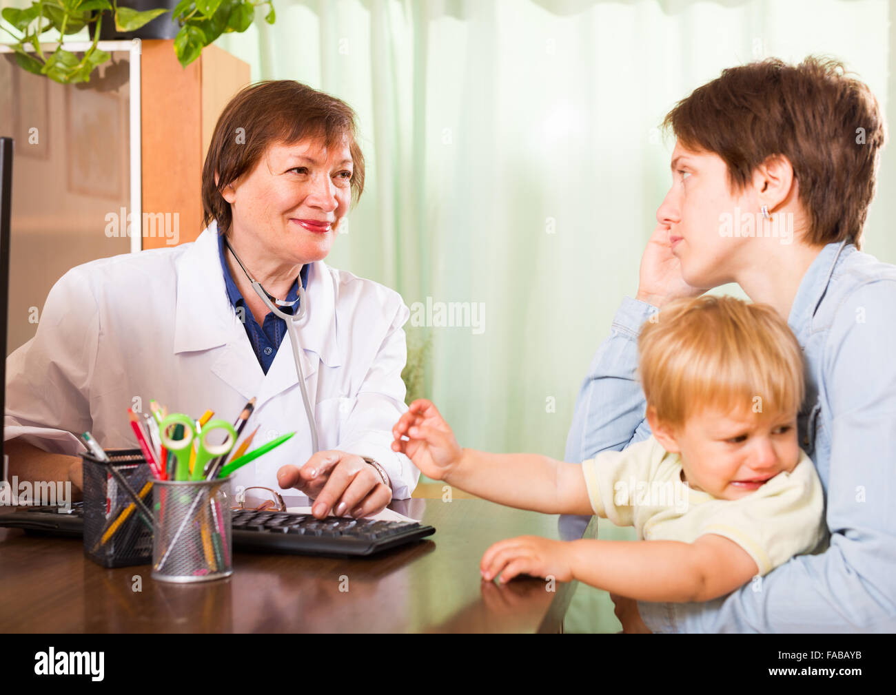 Smiling pediatrician doctor talking with mother of baby at clinic ...