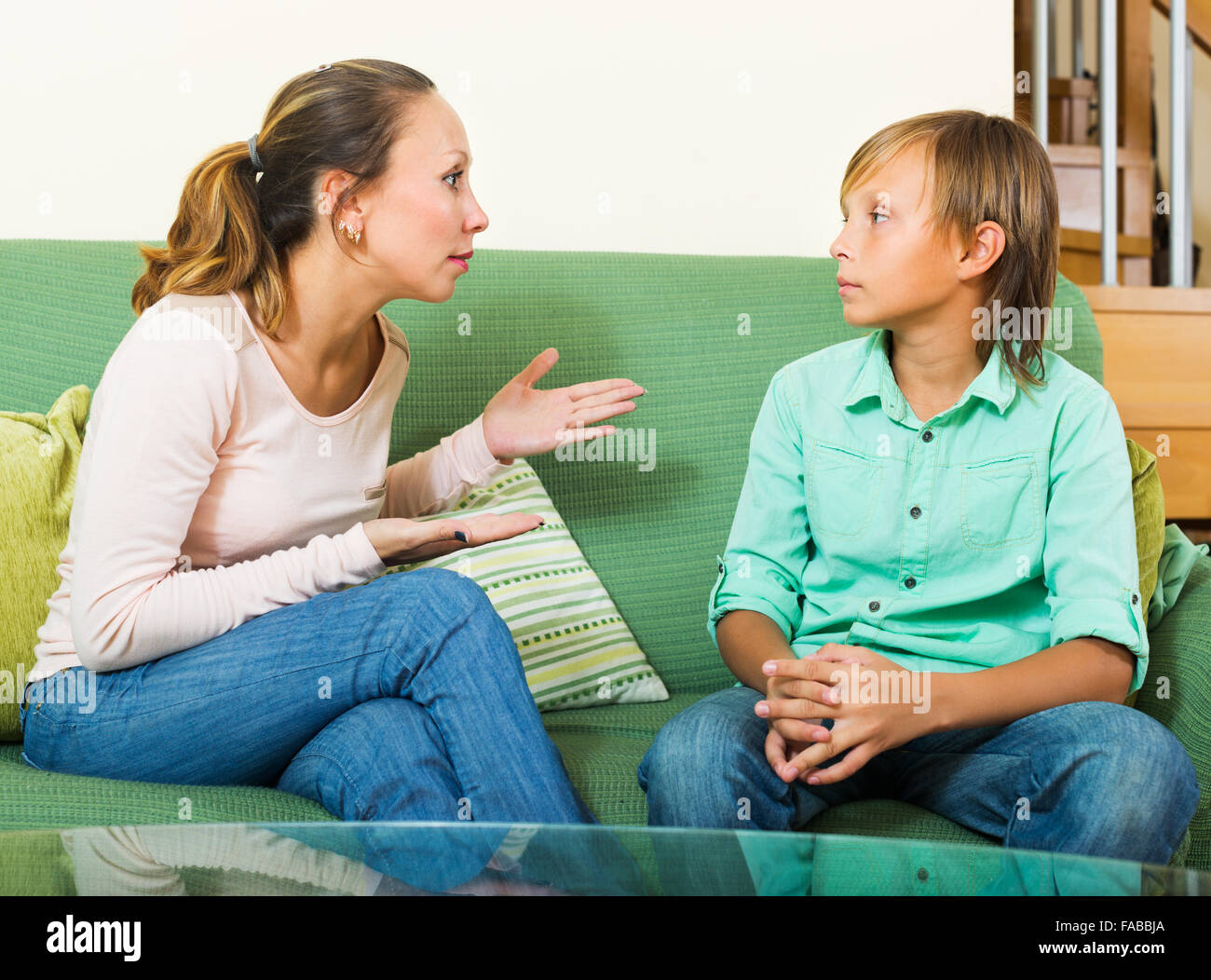 Serious middle-aged mother and teen boy talking in home interior Stock ...