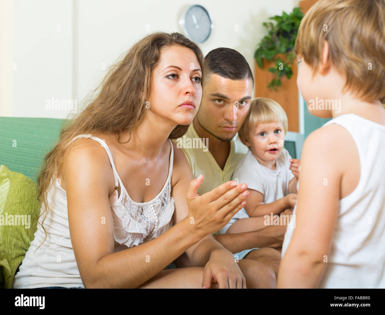 Serious young parents berating little child in living room at home ...
