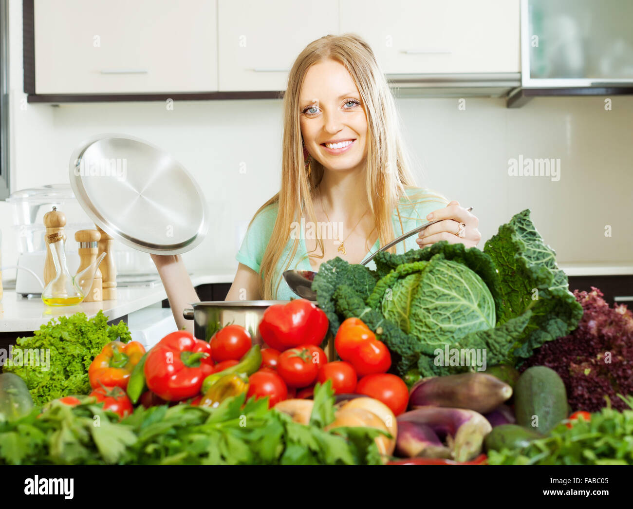 Blonde long-haired woman cooking with vegetables in domestic kitchen Stock Photo - Alamy