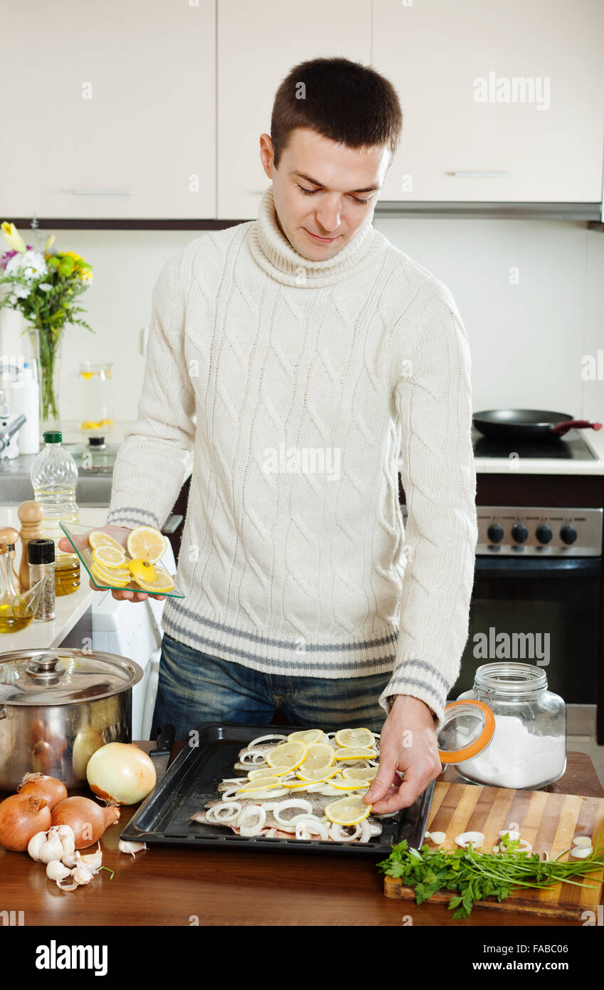 guy cooking trout fish with lemon in roasting pan at home kitchen Stock ...