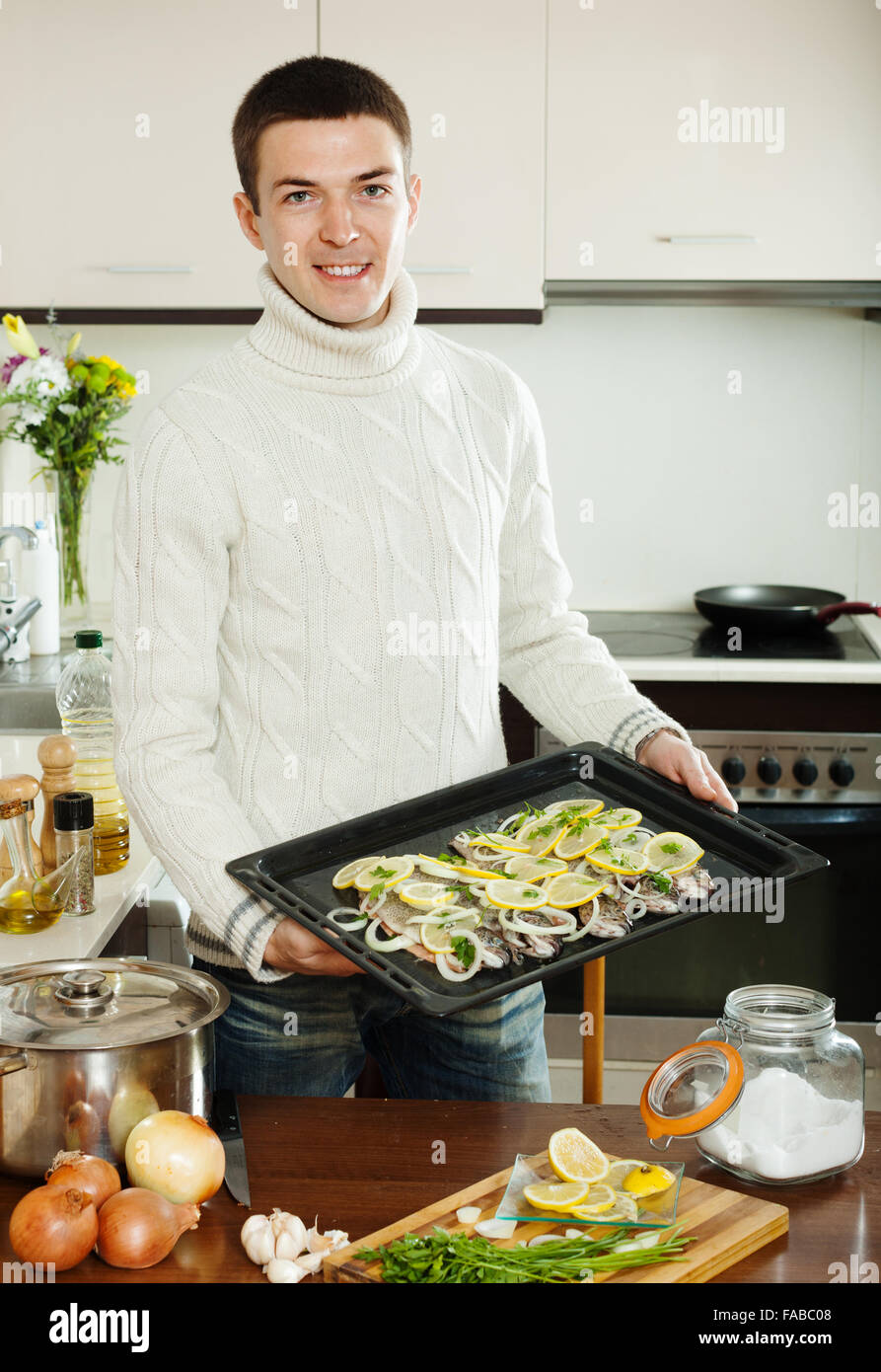 Handsome man with raw fish on roasting pan Stock Photo - Alamy