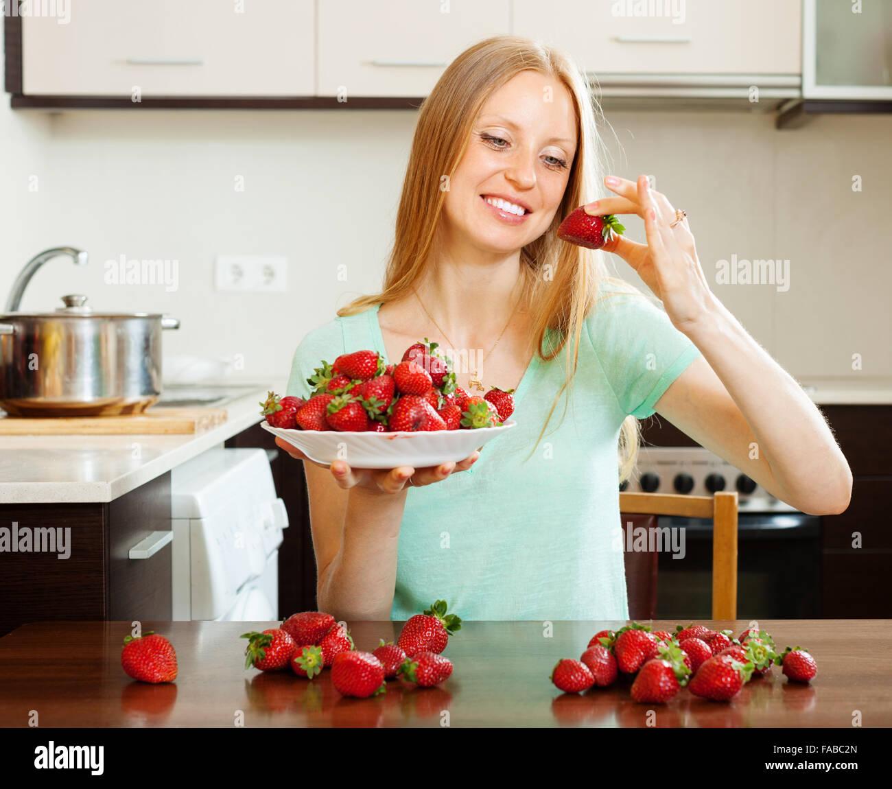 Happy blonde long-haired woman eating strawberry Stock Photo - Alamy