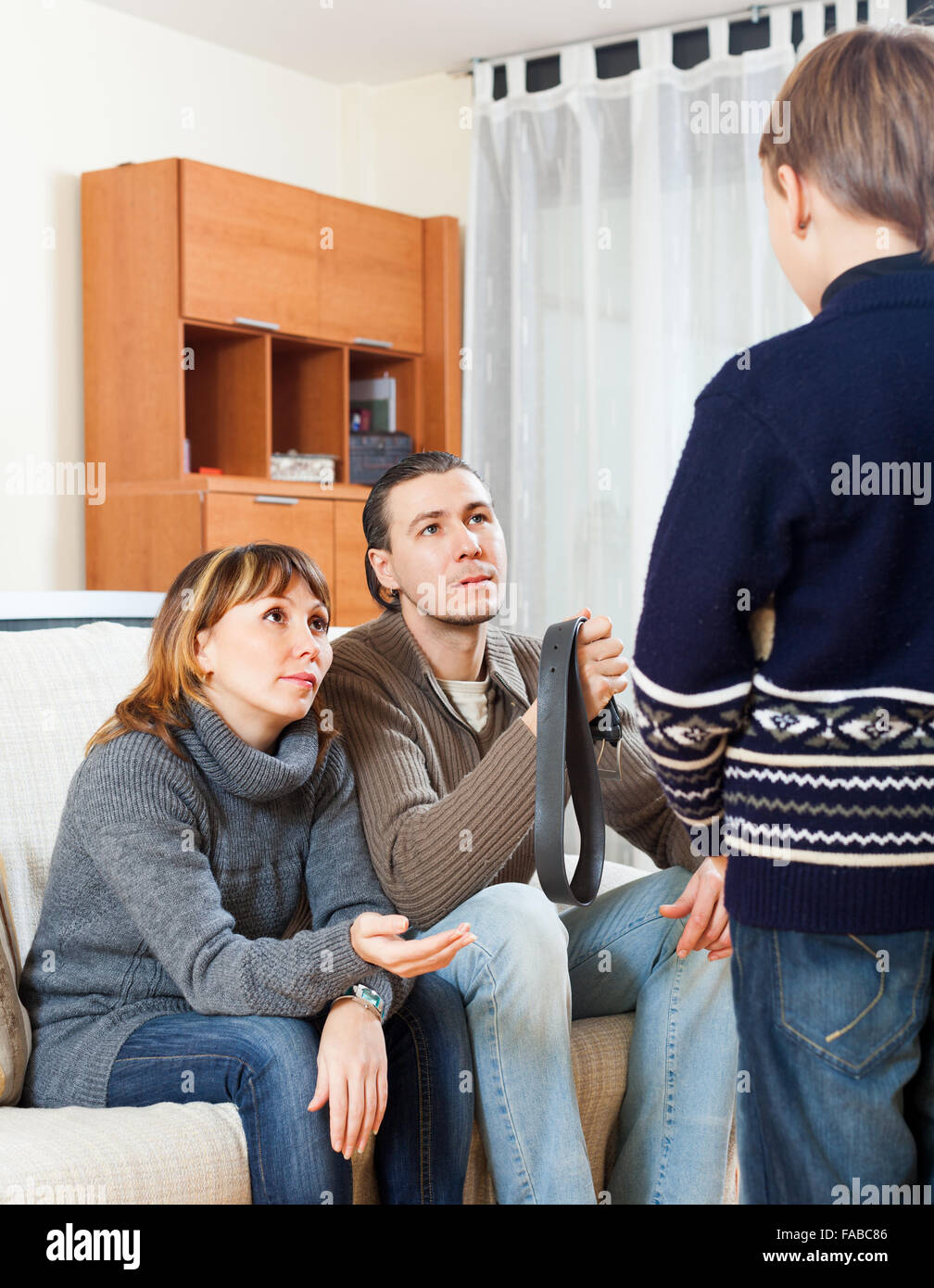 Couple with belt berating teenager boy at home. Focus on parents Stock ...