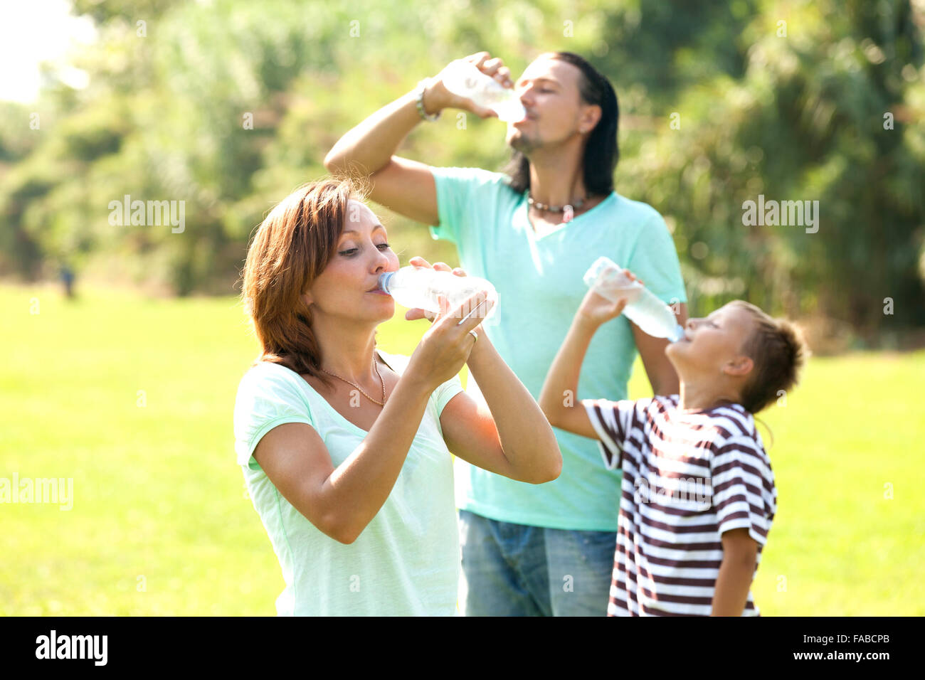 Happy family drinking water from plastic bottles in summer park Stock ...