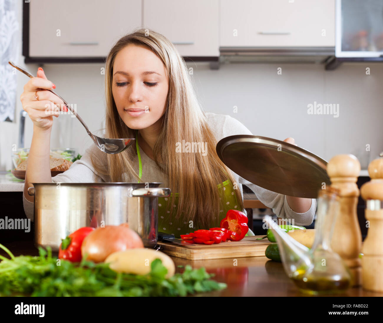 Blonde woman with ladle cooking soup in home kitchen Stock Photo - Alamy
