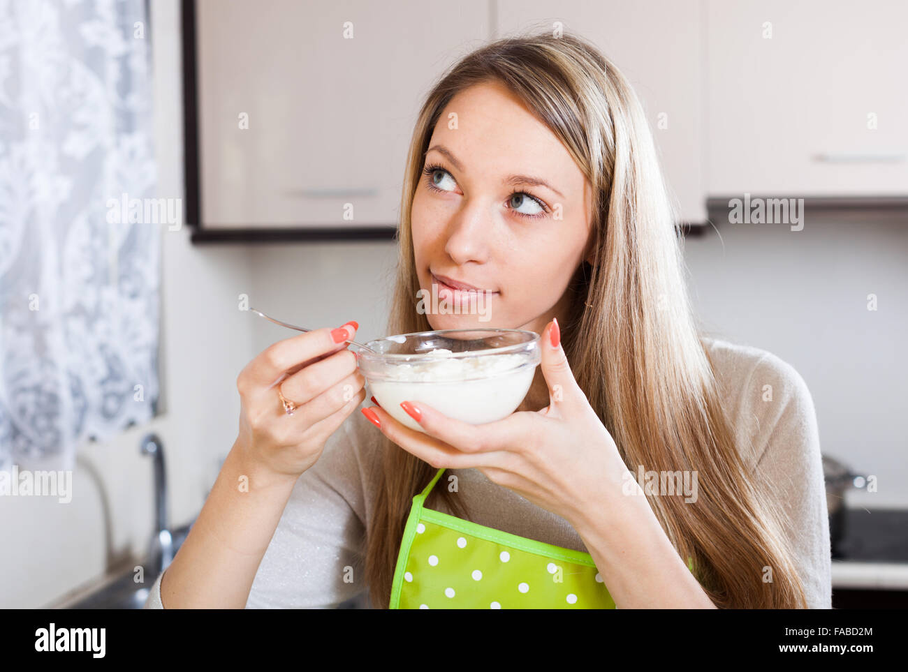 Smiling woman eating curd cheese in kitchen Stock Photo - Alamy
