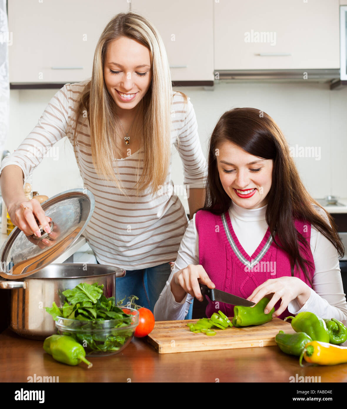 Two smiling women cooking together at them kitchen Stock Photo - Alamy