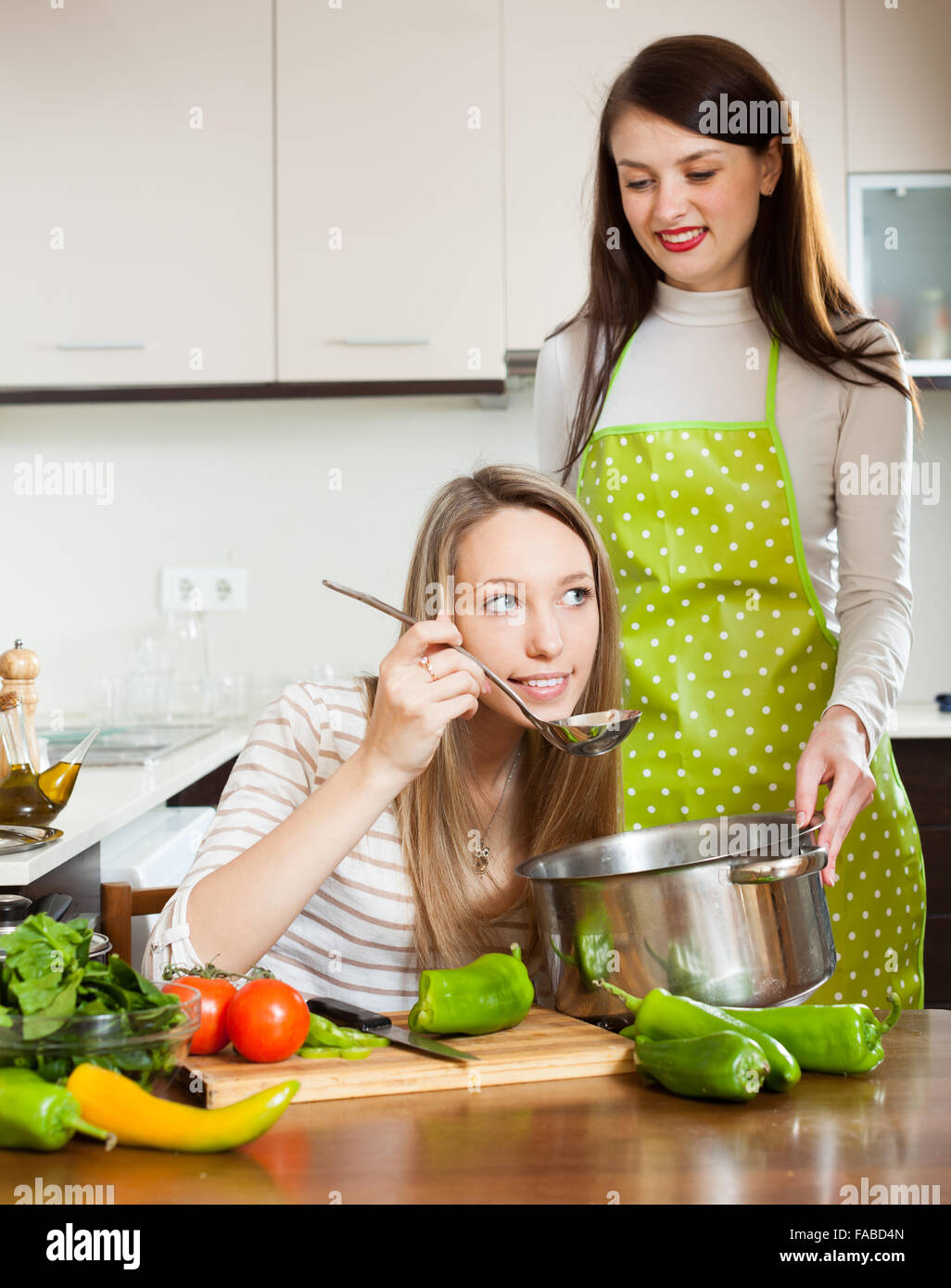 Two women cooking soup together at domestic kitchen. Focus on blonde ...