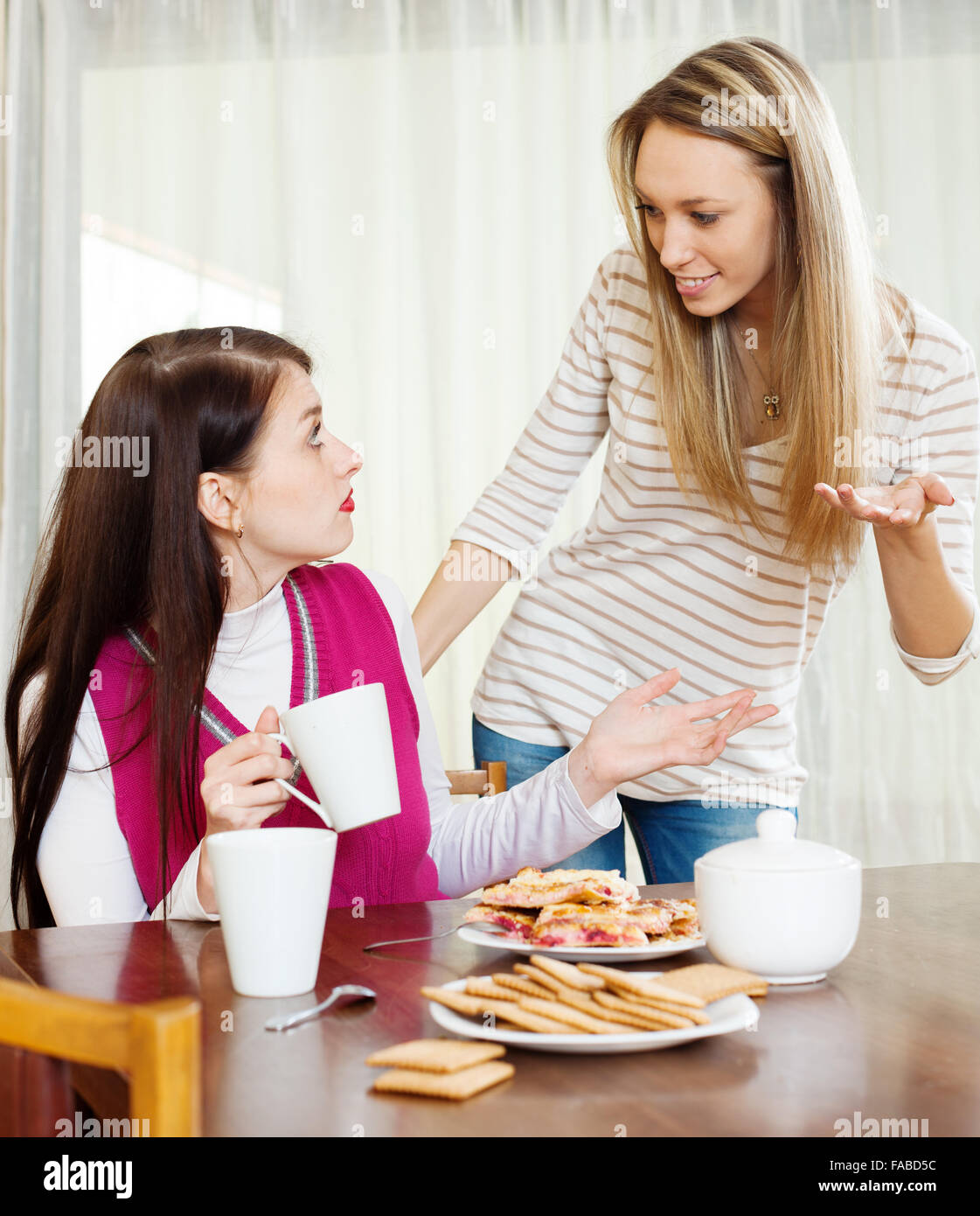 Two women having conflict over tea table in home Stock Photo - Alamy