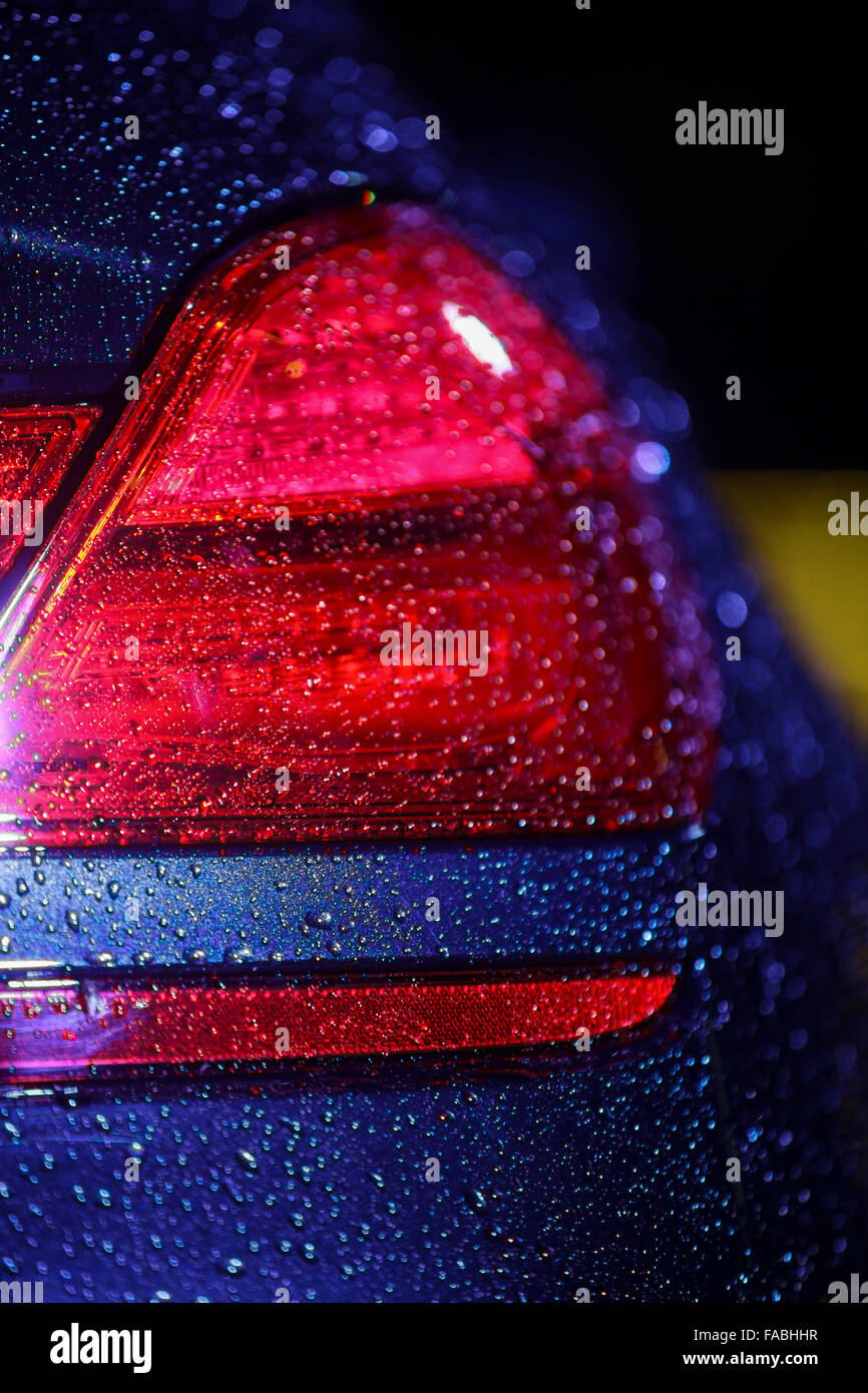 Color image with a car's rear brake light, covered with rain drops ...
