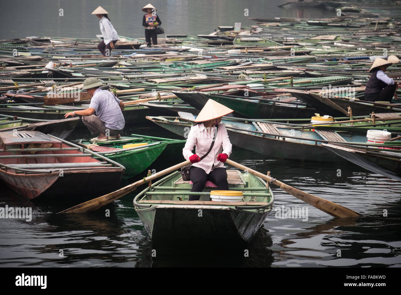 A lady rowing her metal boat amongst the many other boats lined along ...