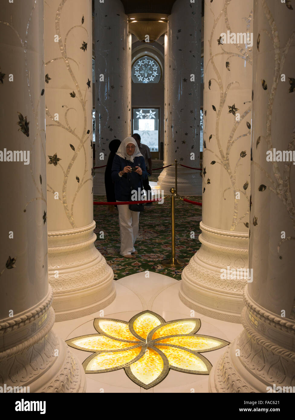 Tourists walking past an ornate wall in Sheikh Zayed Grand Mosque ...