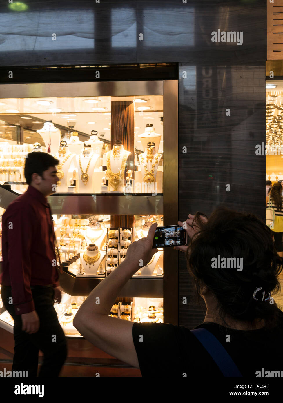 Tourist taking photo of gold window display in Dubai gold souk using a ...