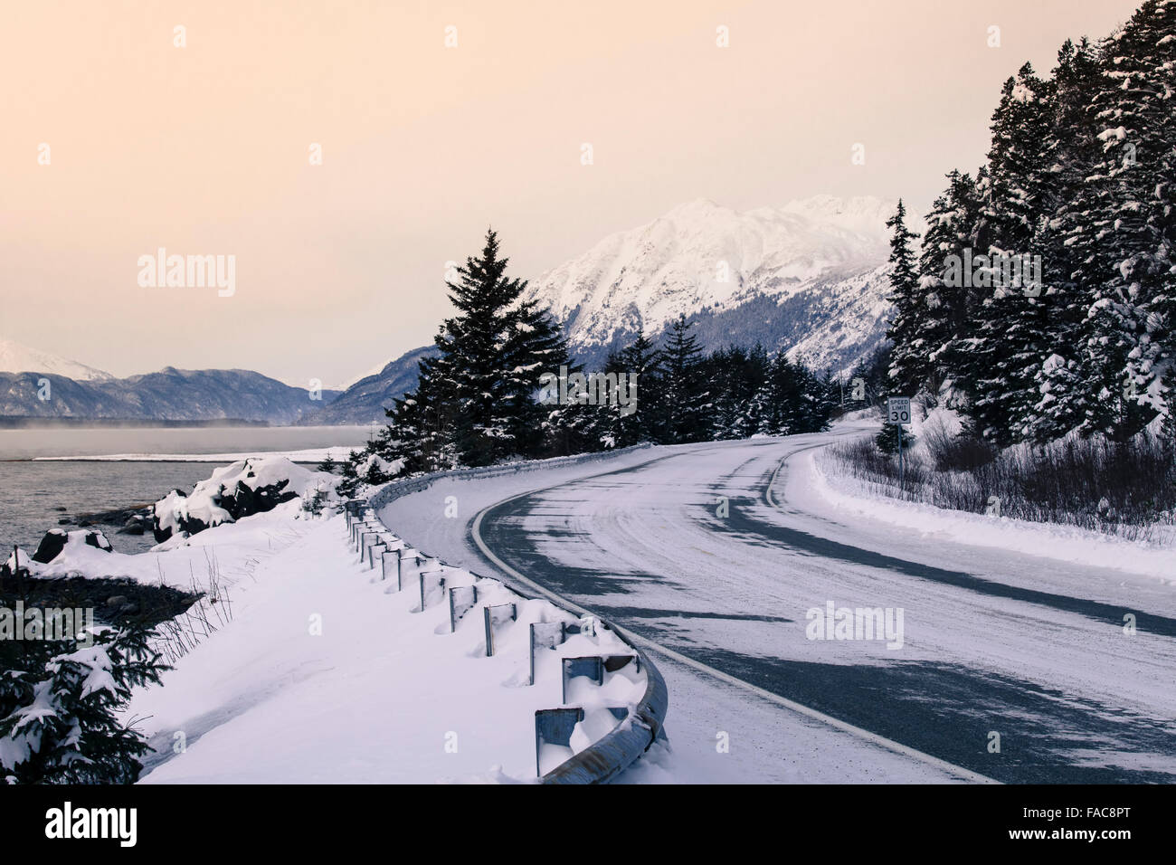 Plowed road in Southeast Alaska near Haines with snow in evening light ...