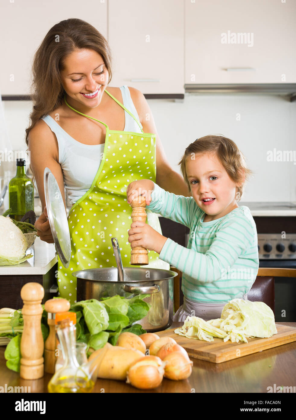 Smiling young woman with little girl cooking at home kitchen Stock ...