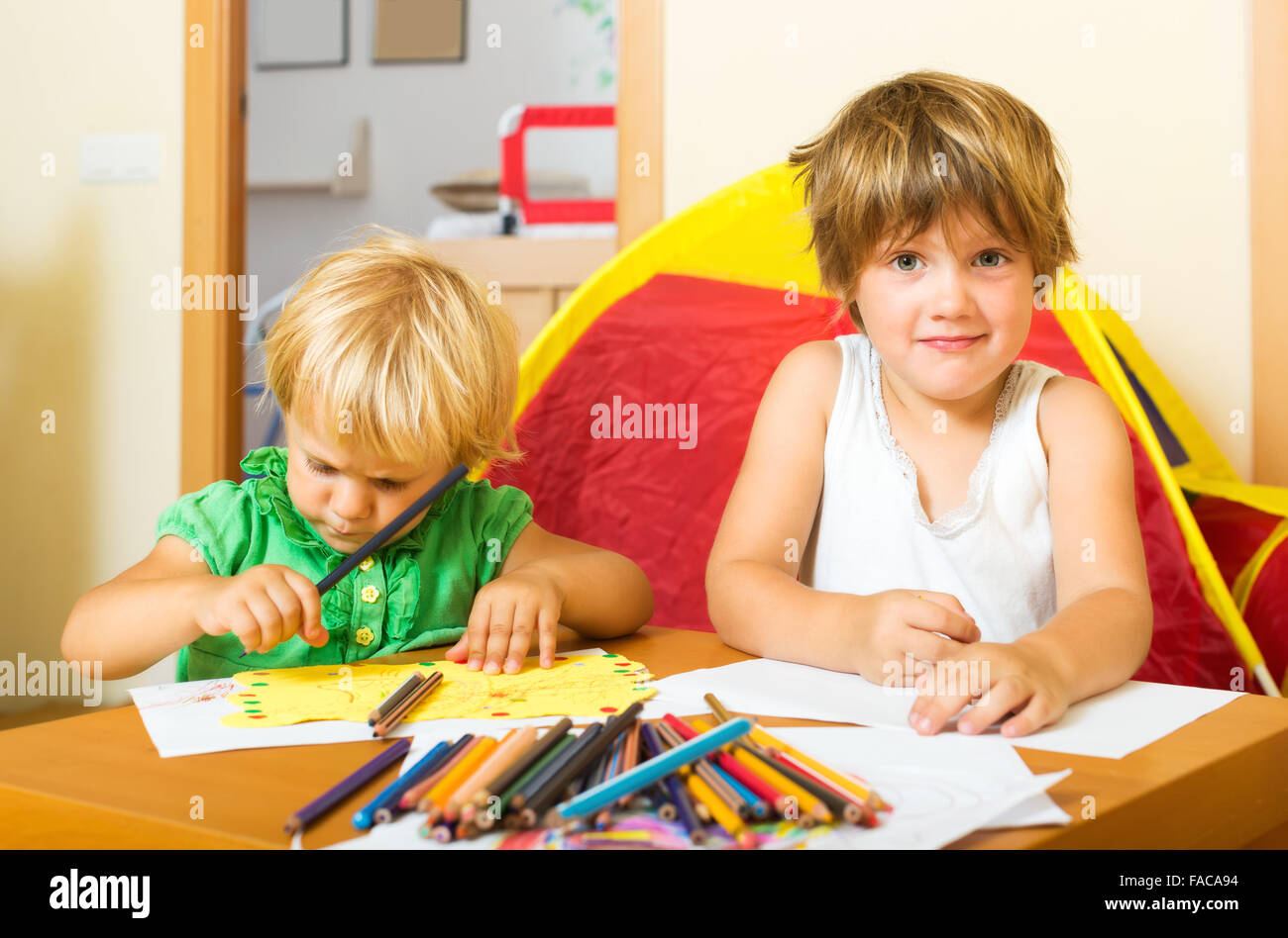 Two little children sketching with paper and pencils in home interior ...