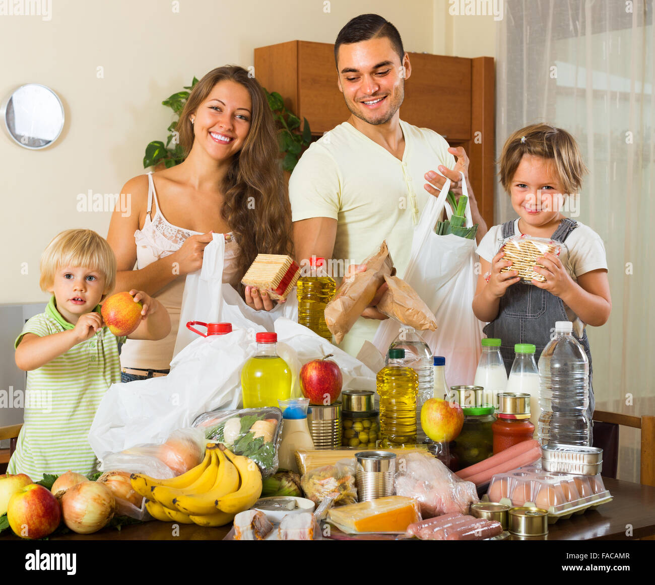 Happy parents with female children sorting purchased food out indoor ...