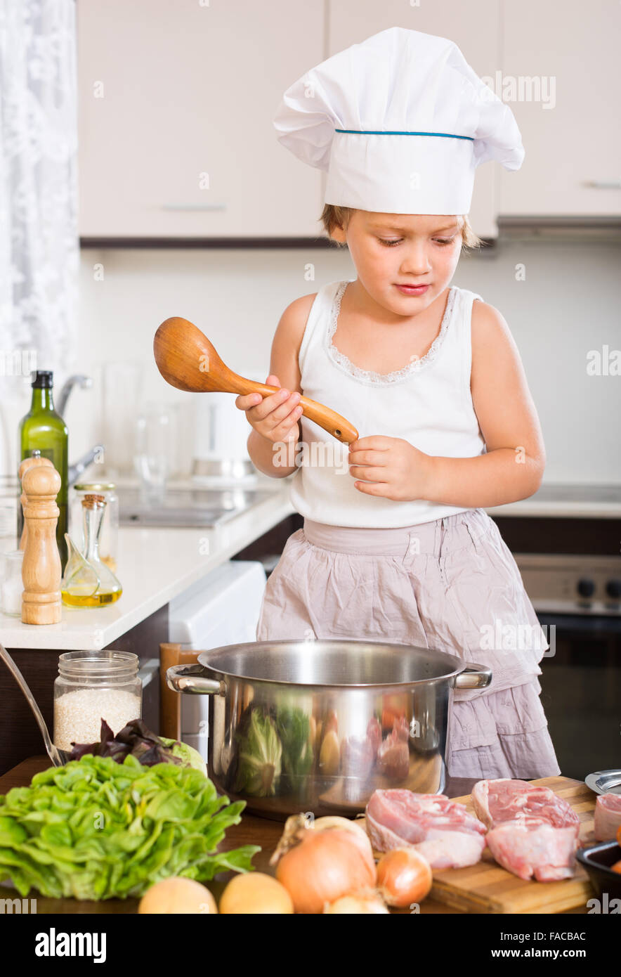 Happy little girl cooking with meat at home kitchen Stock Photo - Alamy