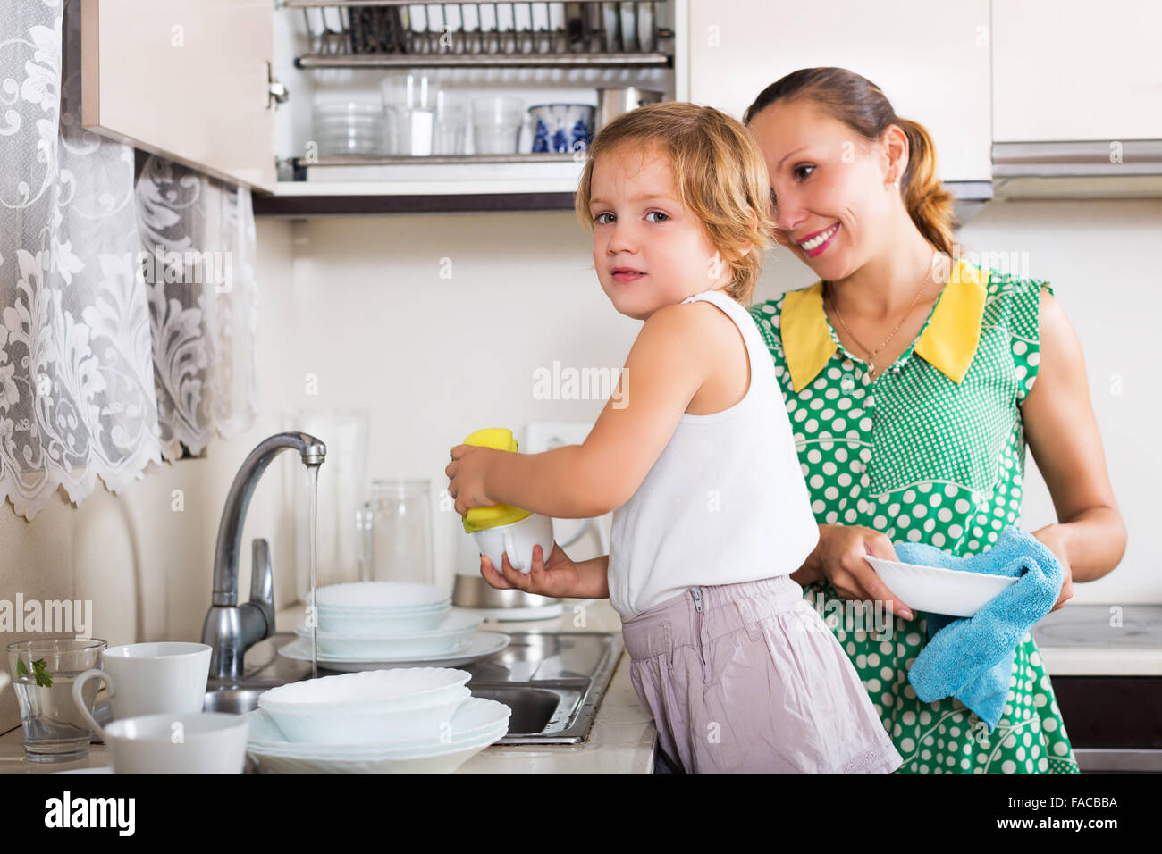 Daughter with mother washing plates in kitchen Stock Photo - Alamy