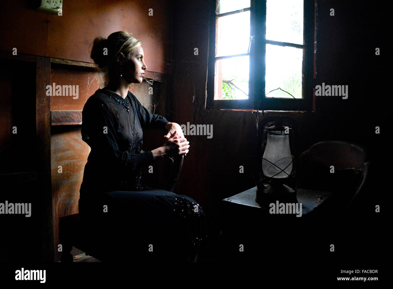 YOUNG WOMAN IN BLACK DRESS WAITING BY A WINDOW Stock Photo - Alamy