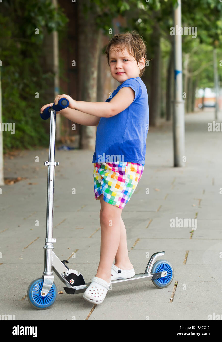 Happy active little girl riding on scooter in park Stock Photo - Alamy