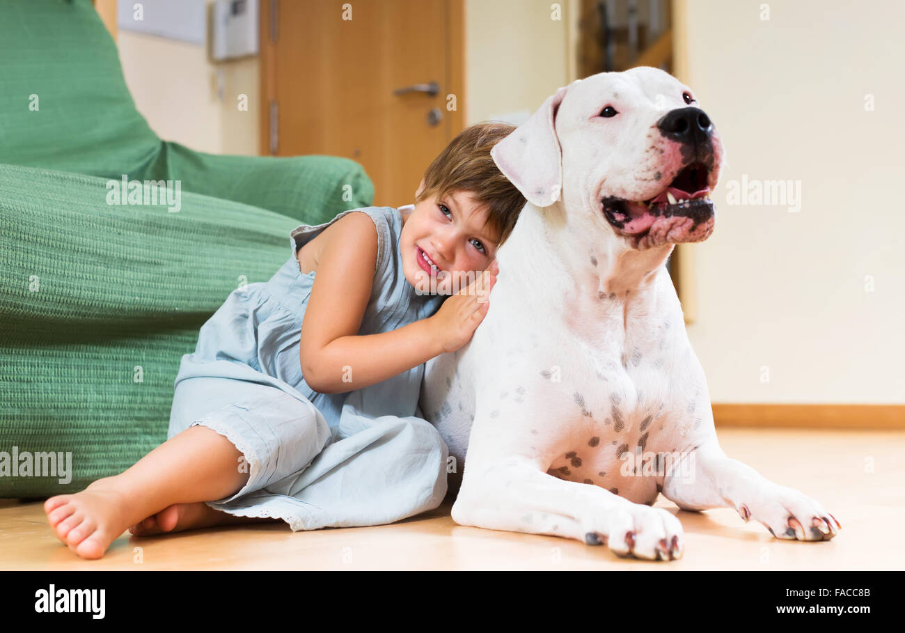 Happy little girl hugging big white dog on the floor at home Stock ...