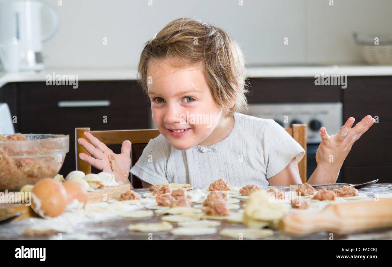 Playful little girl cooking meat dumplings from meat stuffing and dough ...