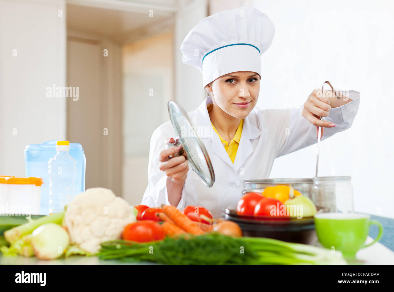 Cook in white hat looks into the saucepan in kitchen Stock Photo - Alamy