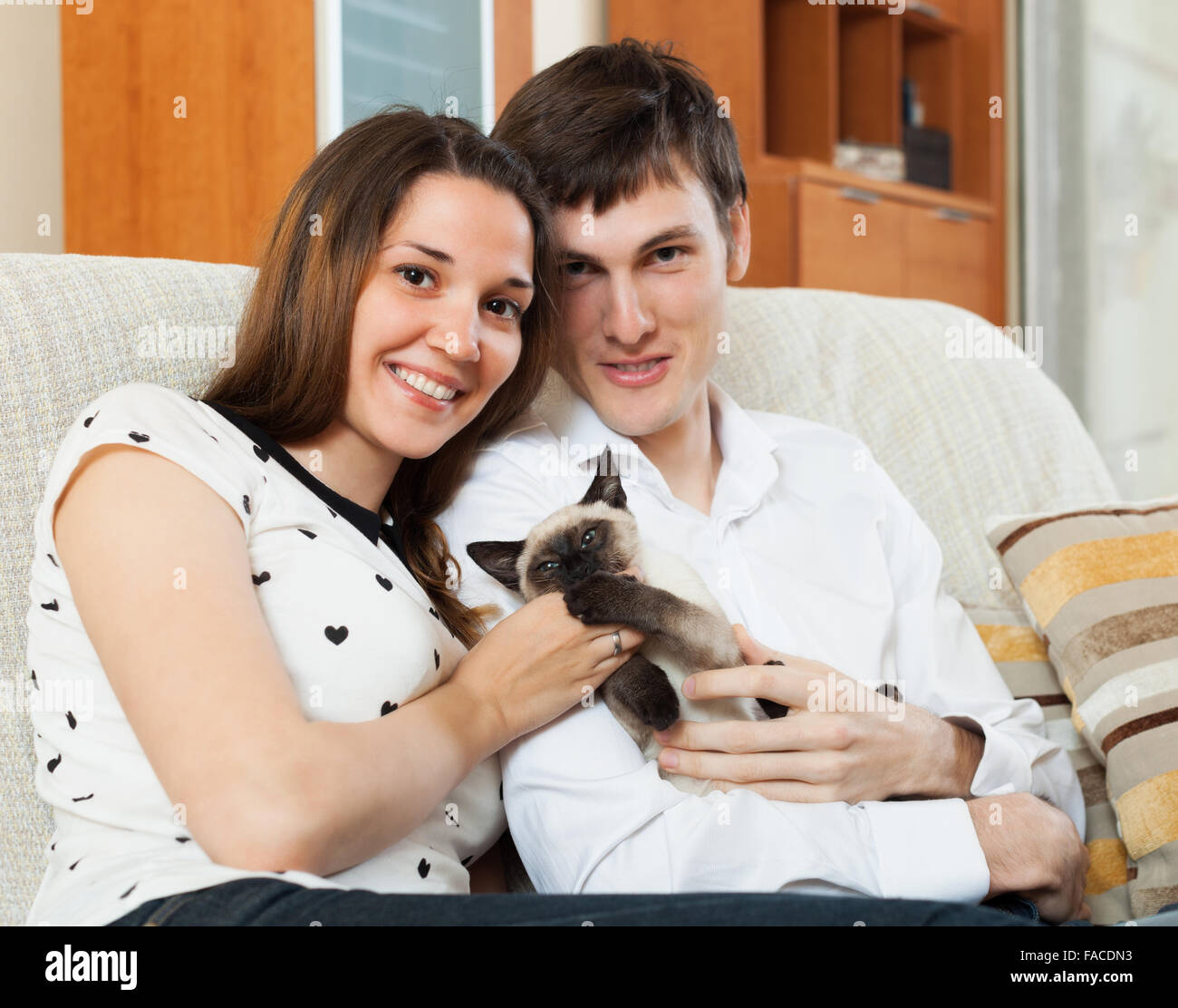 Loving man and woman with kitten in home interior Stock Photo - Alamy