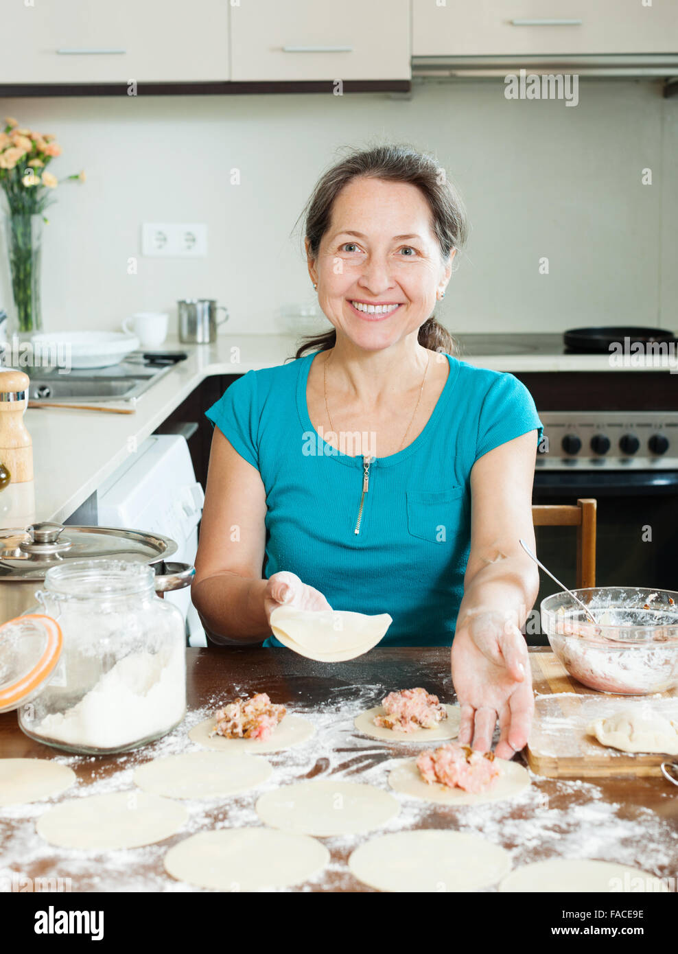 Mature woman making dumplings from meat stuffing and dough Stock Photo ...