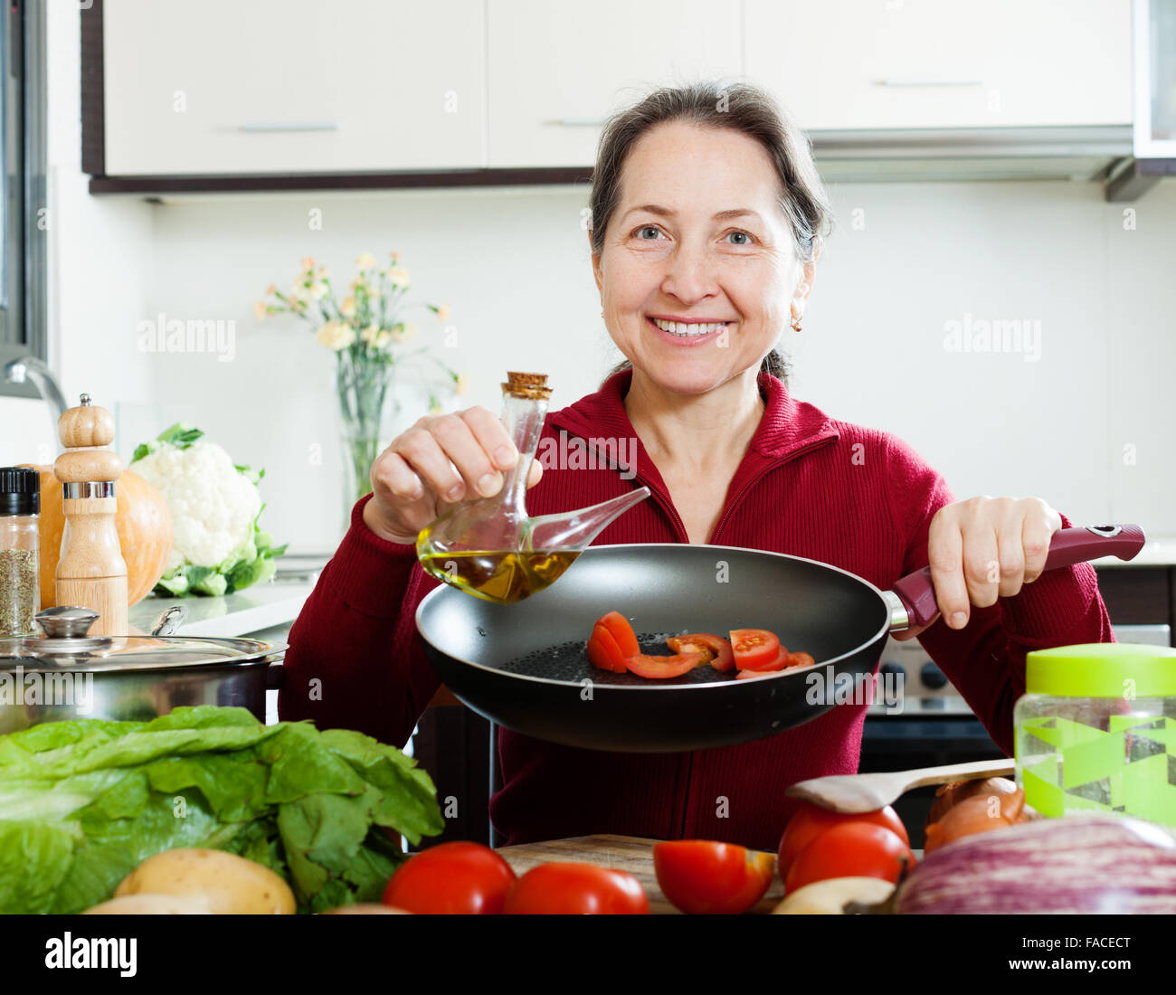 Happy woman pouring oil into girdle at kitchen Stock Photo - Alamy