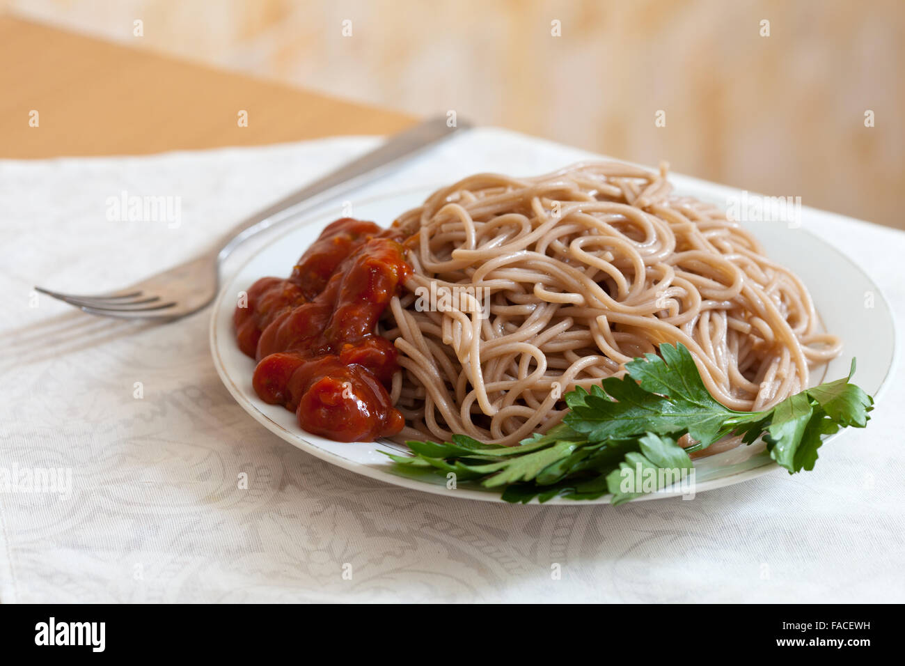Buckwheat spaghetti pasta with ketchup on white plate at table Stock ...