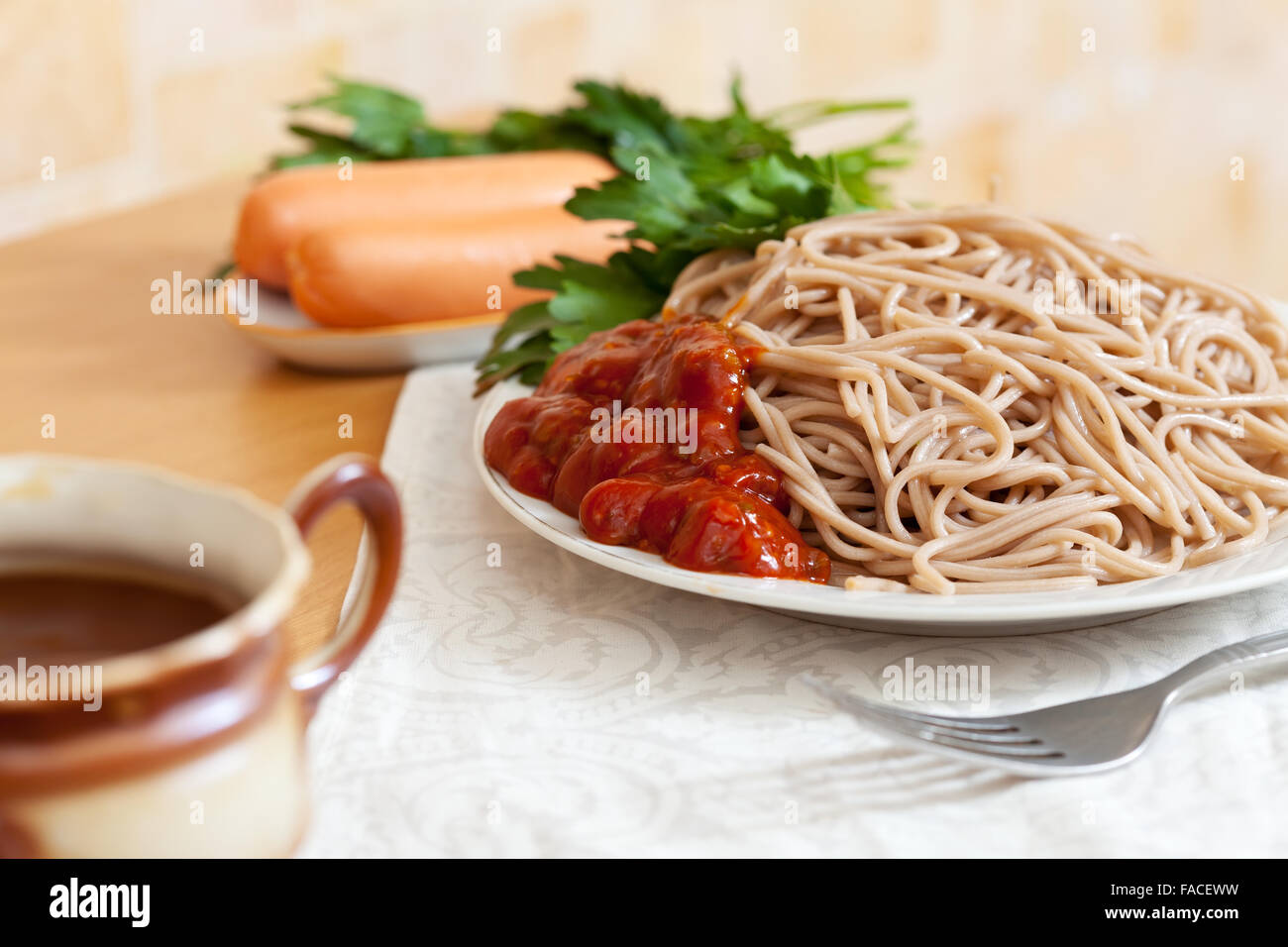 Supper. Spaghetti pasta with catchup and sausages in plates on table ...