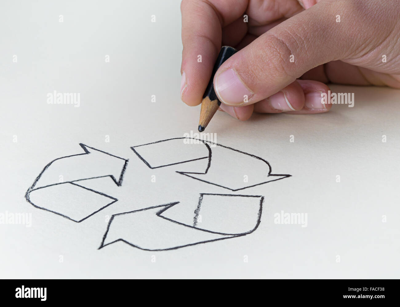 A child drawing the recycling symbol with a very short pencil stub ...