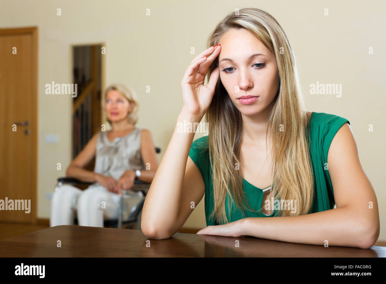 Tired woman and disabled person on chair indoor Stock Photo - Alamy