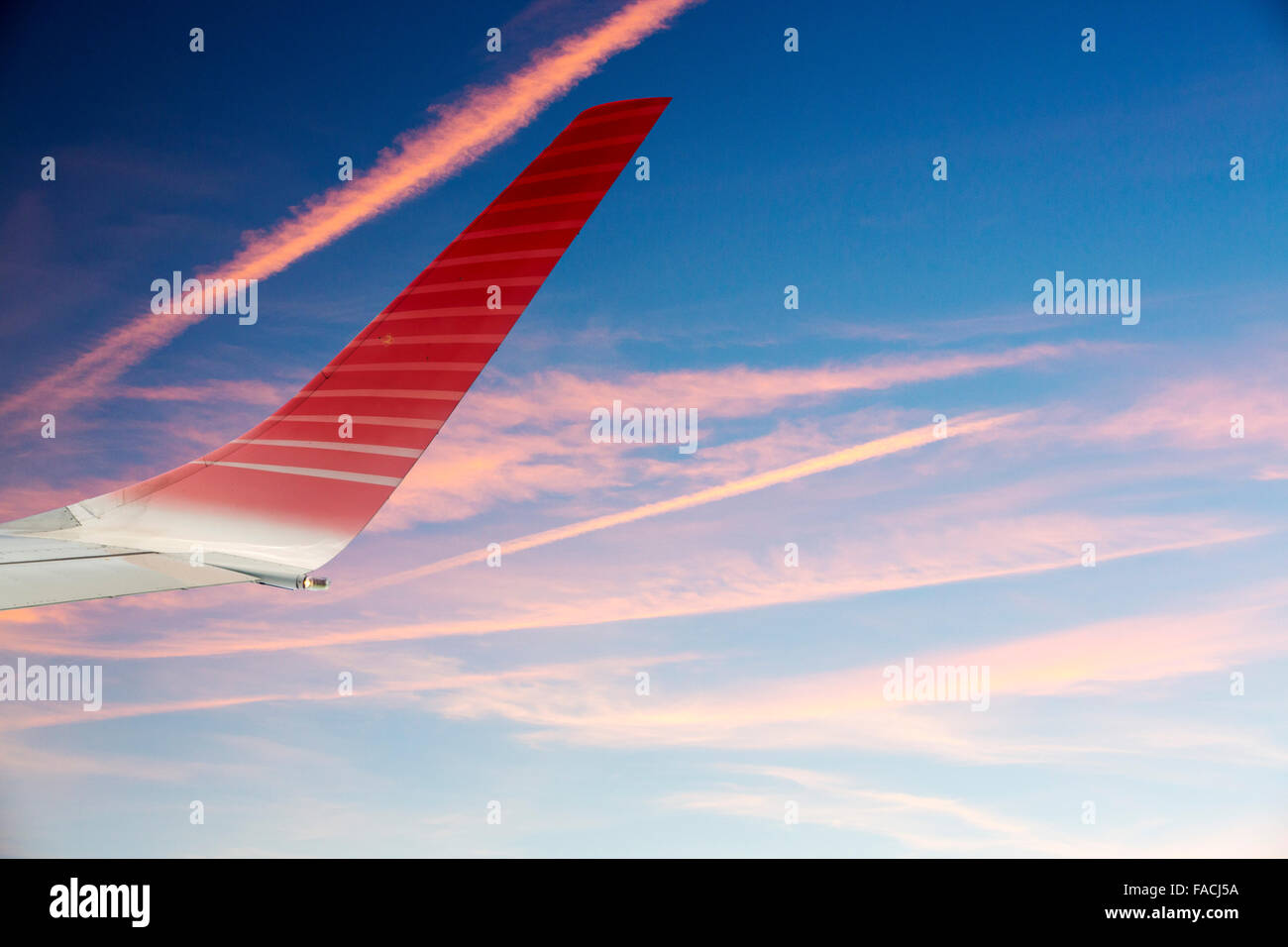Vapour trails lit by the setting sun and a plane wing Stock Photo - Alamy
