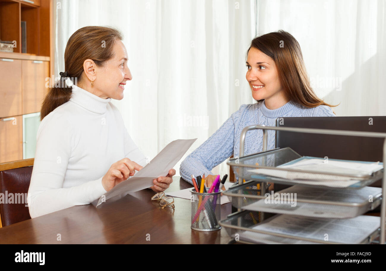 woman filling questionnaire for mature employee with paper at door ...