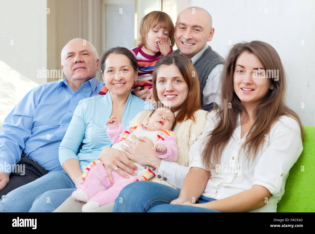 cheerful three generations family sits on sofa in home interior Stock ...